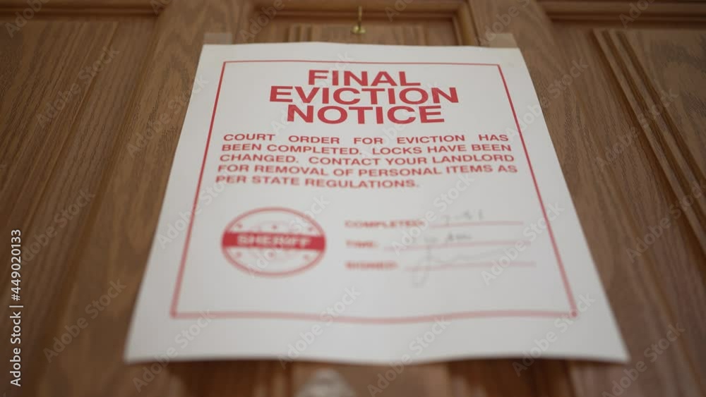A dramatic low angle view of an eviction notice on a home's front door ...
