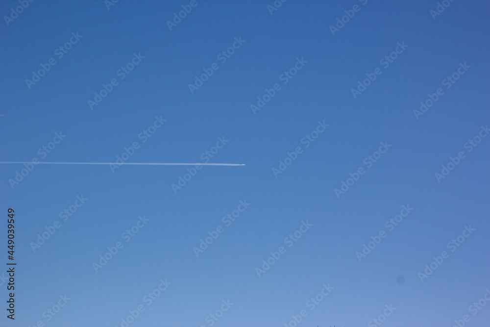 Inversion trail of clouds from the plane against the blue sky. Airplane ...