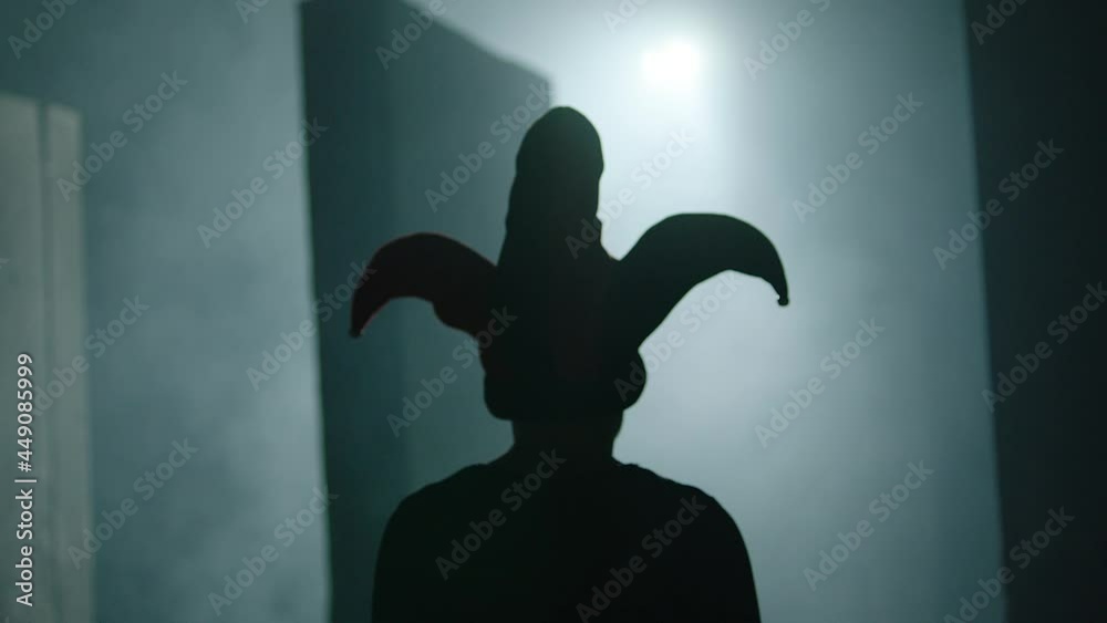 Evil clown , jester or joker running and jumping inside dark maze ...