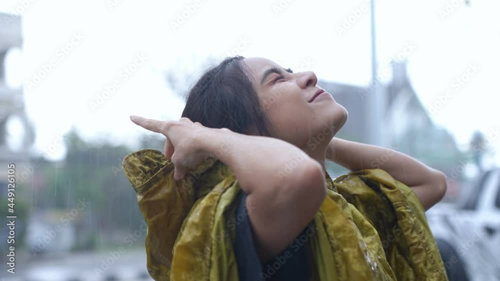 Asian girl take off raincoat hoodie to enjoy the falling rain, standing ...