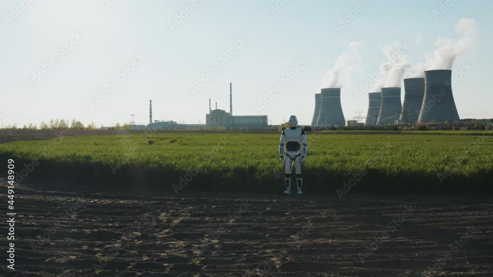 Automated cyborg prototype standing against industrial massive factory ...