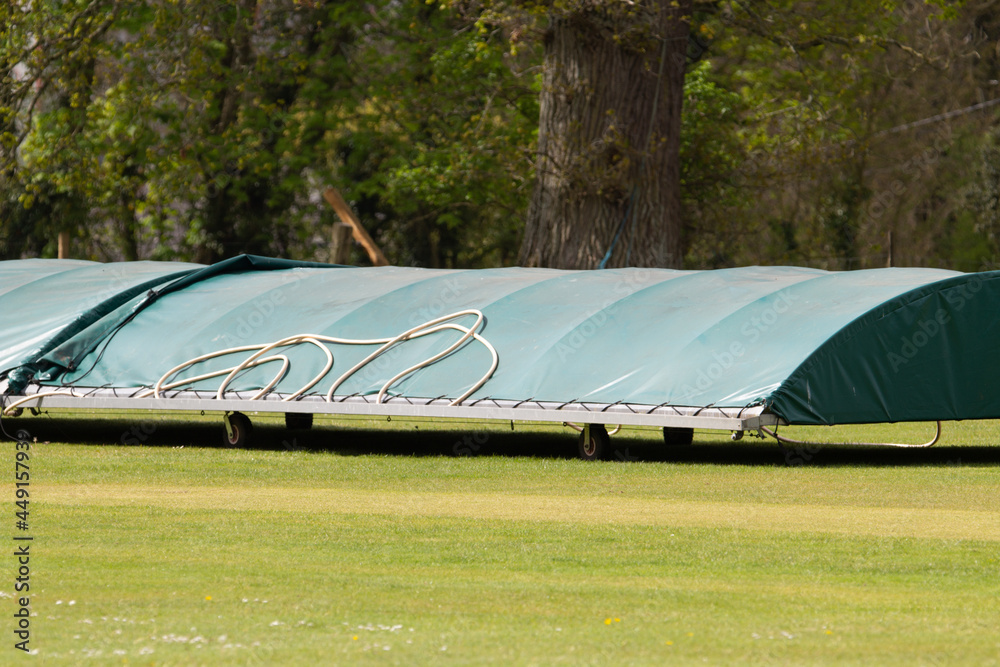 cricket covers and hose pipe on a cricket pitch with oak trees in the ...