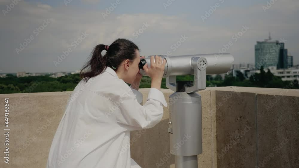 Young traveler woman using binoculars on building roof for sightseeing ...