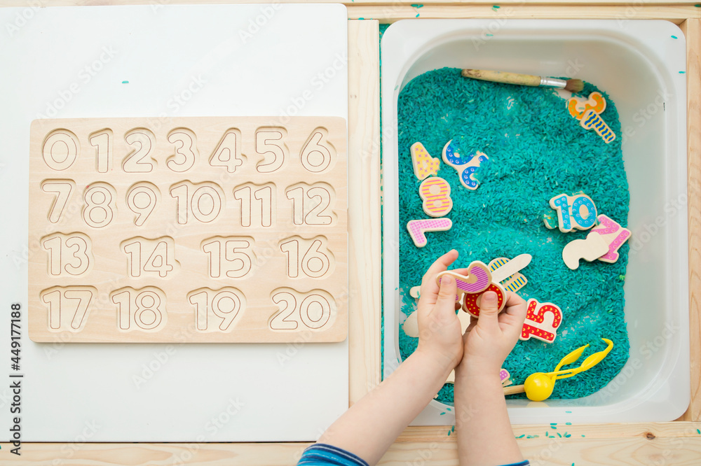 Kid learning numbers through game. Sensory activity with colored rice ...