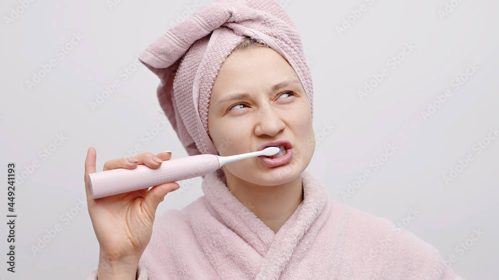 Cute girl holding an electric toothbrush. Brushing her teeth. The girl ...