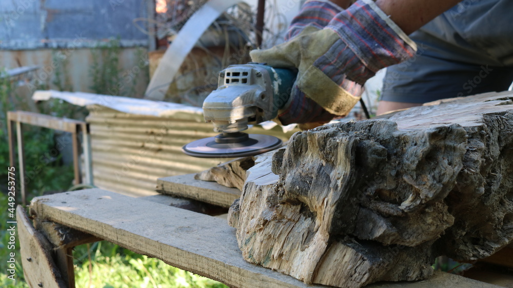 grinder processing of a piece of solid wood in the open air ...