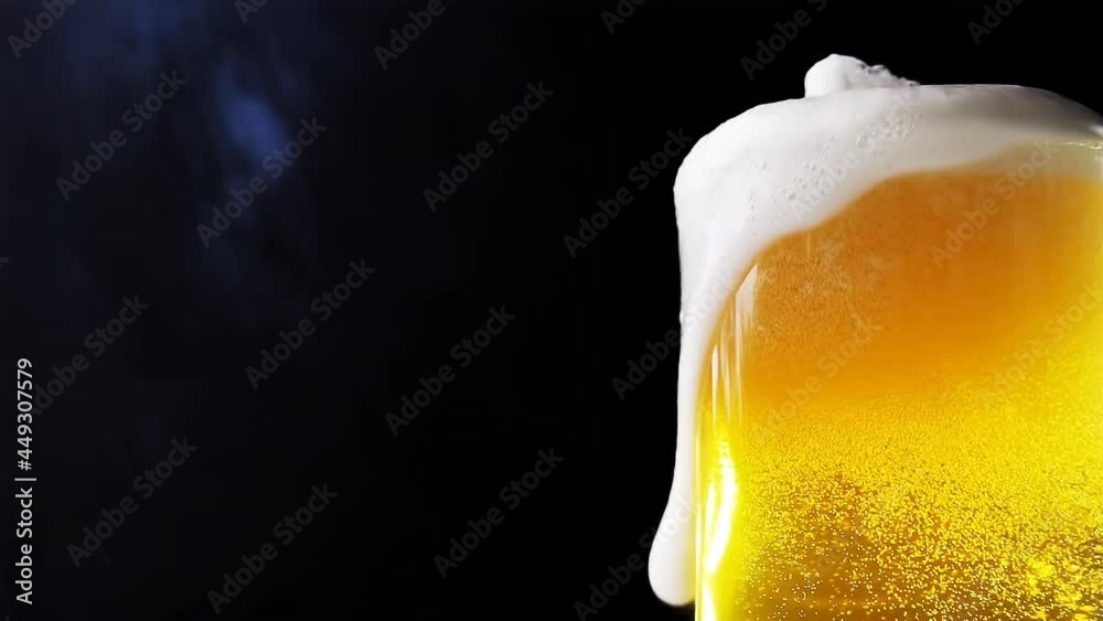 Beer is pouring into a beer mug with bubbles close-up on a black ...