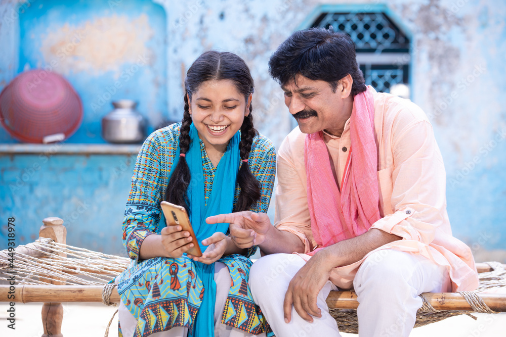 Happy Indian father and young daughter using smartphone while sitting ...