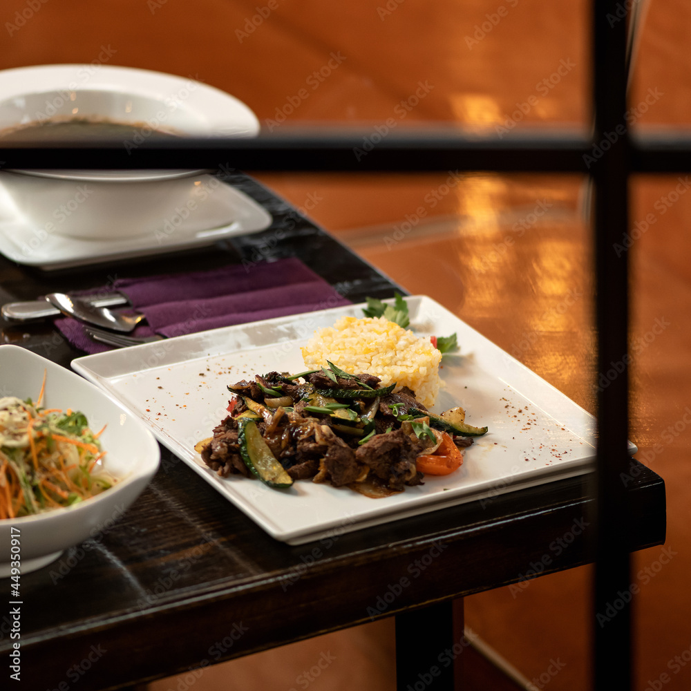 Platter with stewed rice, meat and vegetables. Set lunch on table ...