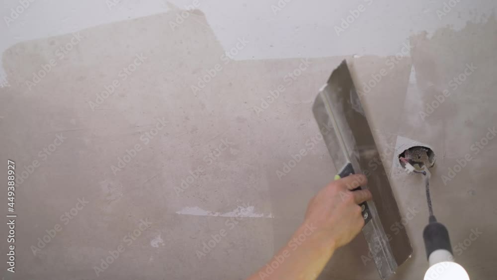 Worker hands with putty knife and plaster old cement ceiling with putty ...