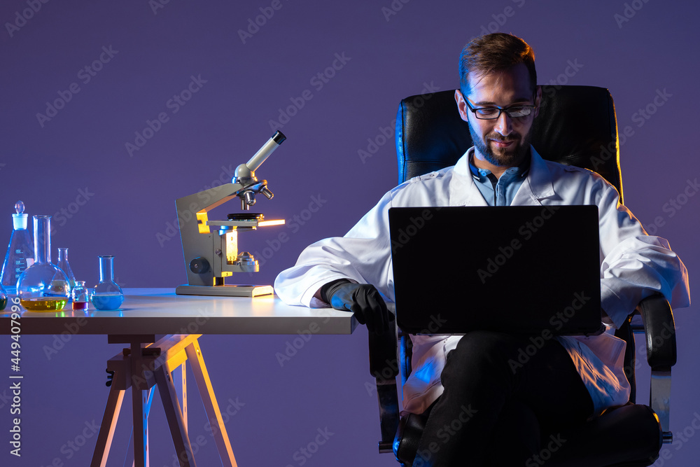 Laboratory technician looks into laptop and smiles. Laboratory ...