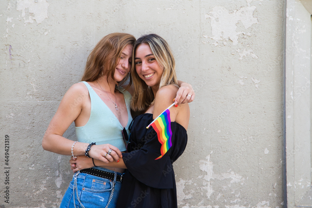 Beautiful young women are hugging each other with a gay pride flag in ...