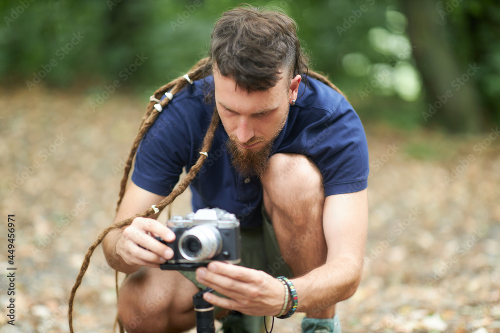 Young artist with dreadlocks setting up his digital camera on a gimbal ...