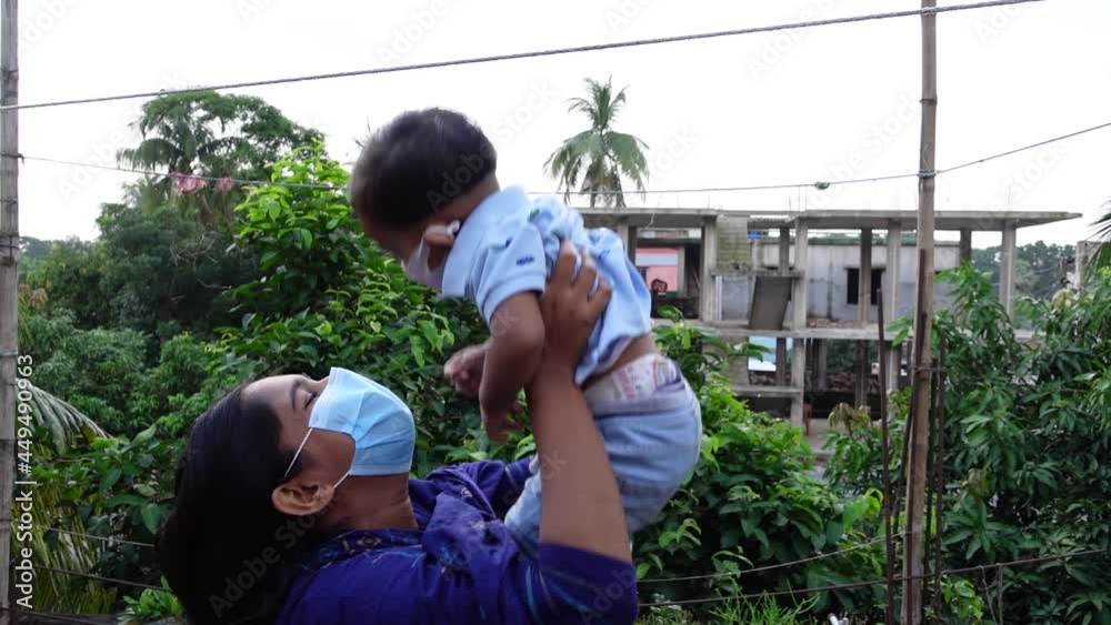 Mother and child wearing safety masks are having fun. The baby is ...
