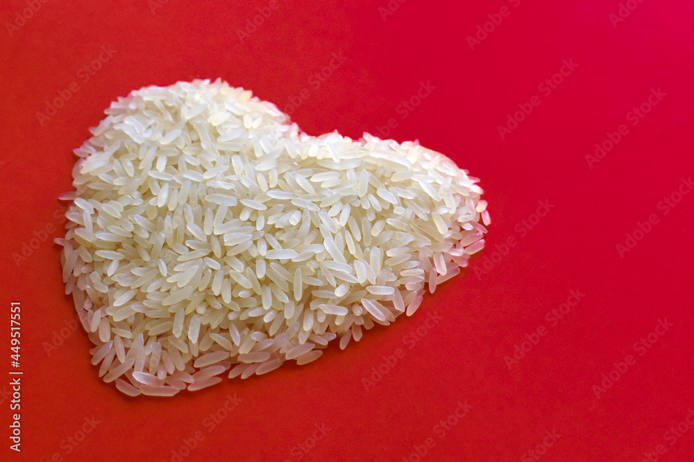 Heart shape of parboiled rice on red background. Copy space is on the ...