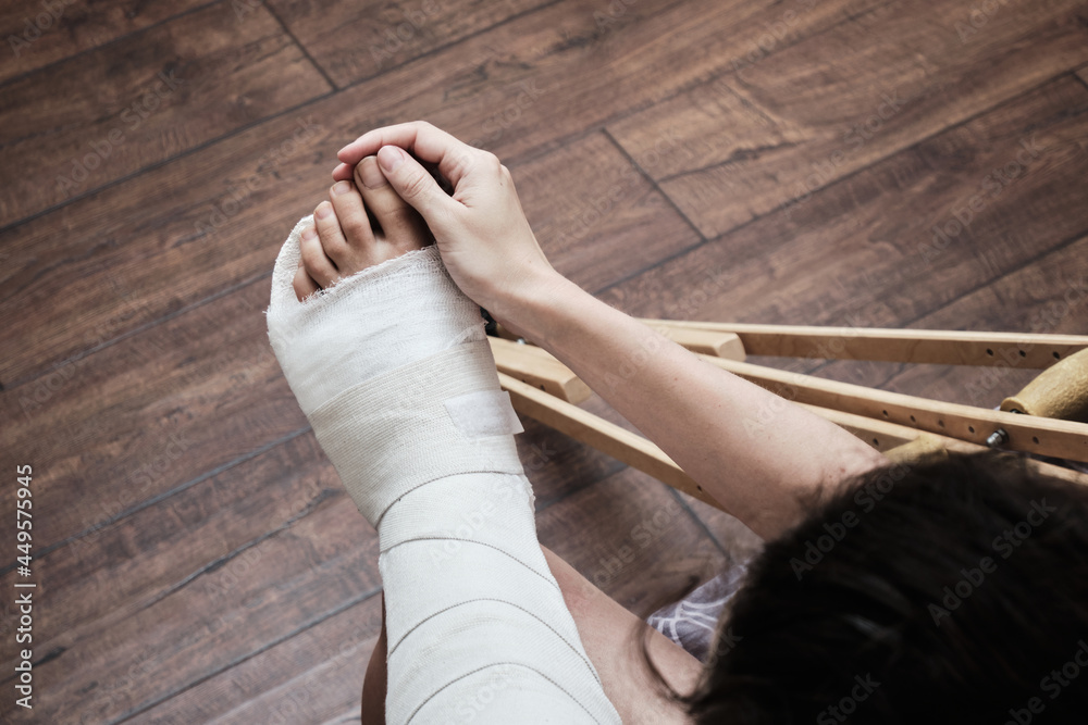 A woman massages the toes of a broken leg with her hands. Top view of a ...