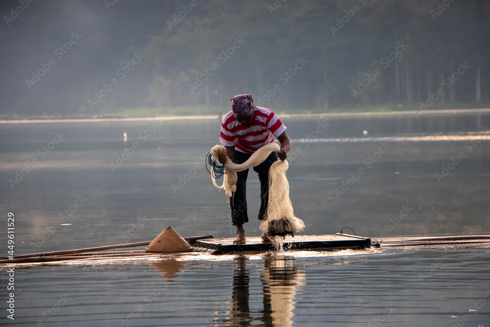 fishermen cast nets to catch fish on bamboo rafts. crossing the lake by ...