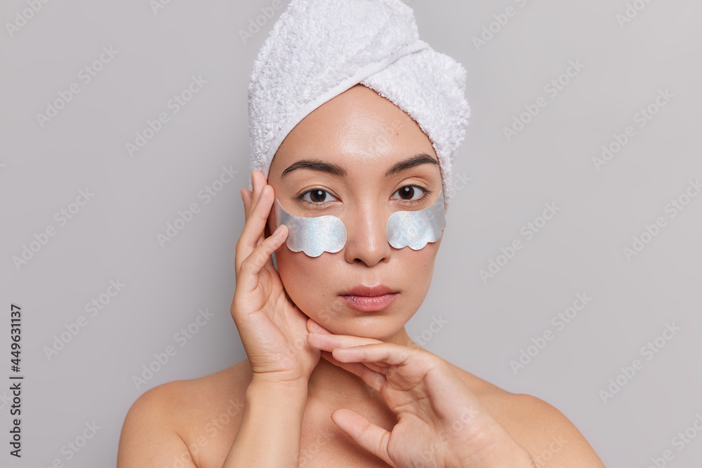 Portrait of serious Asian woman keeps hands tenderly near face looks ...