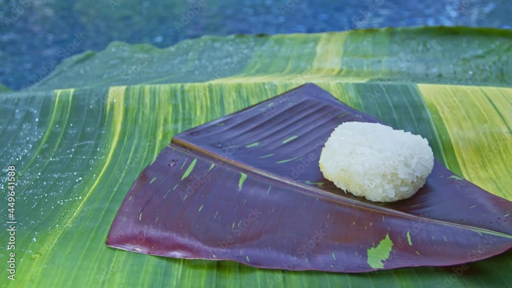 .Mango sticky rice served on a spotted banana leaf by the pool ...