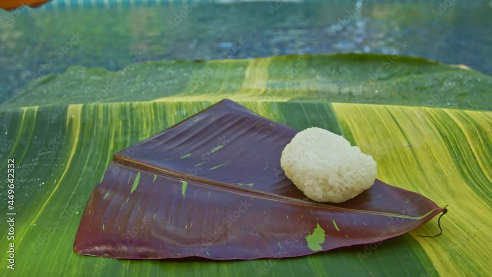 .Mango sticky rice served on a spotted banana leaf by the pool ...