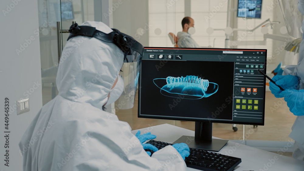 Team of orthodontists examining radiography of dentition on modern ...