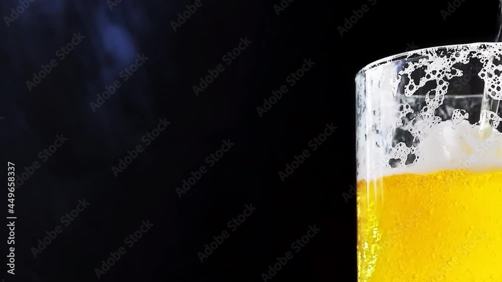 Beer is pouring into a beer mug with bubbles close-up on a black ...
