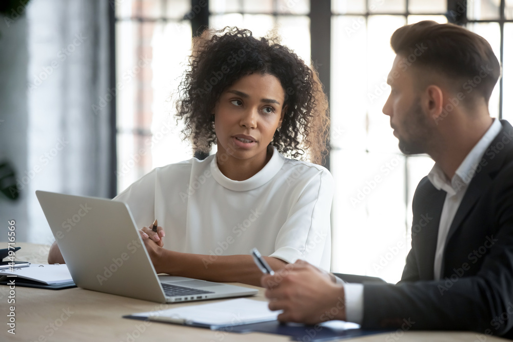 Serious young multiracial diverse businesspeople sit at desk in office ...