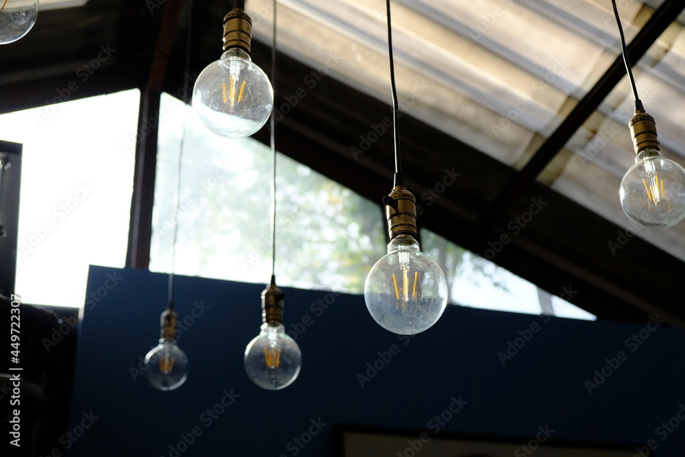 Incandescent light bulb hanging from ceiling over head from roof house ...