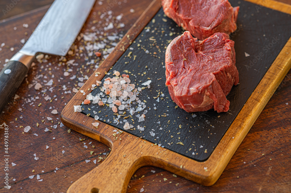 Raw Hereford grass fed beef tenderloin on black slade board with salt ...