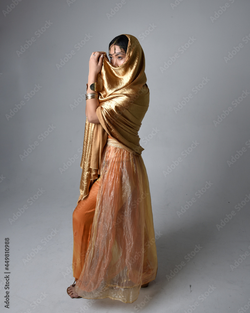 Full length portrait of pretty young asian woman wearing golden Arabian ...