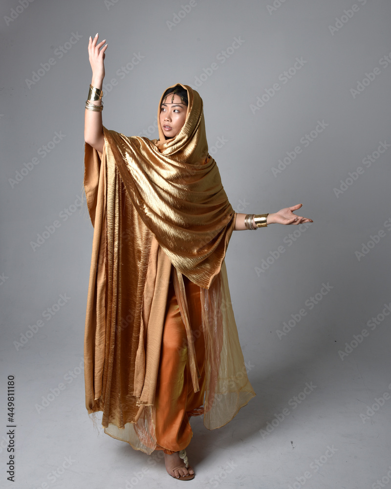 Full length portrait of pretty young asian woman wearing golden Arabian ...