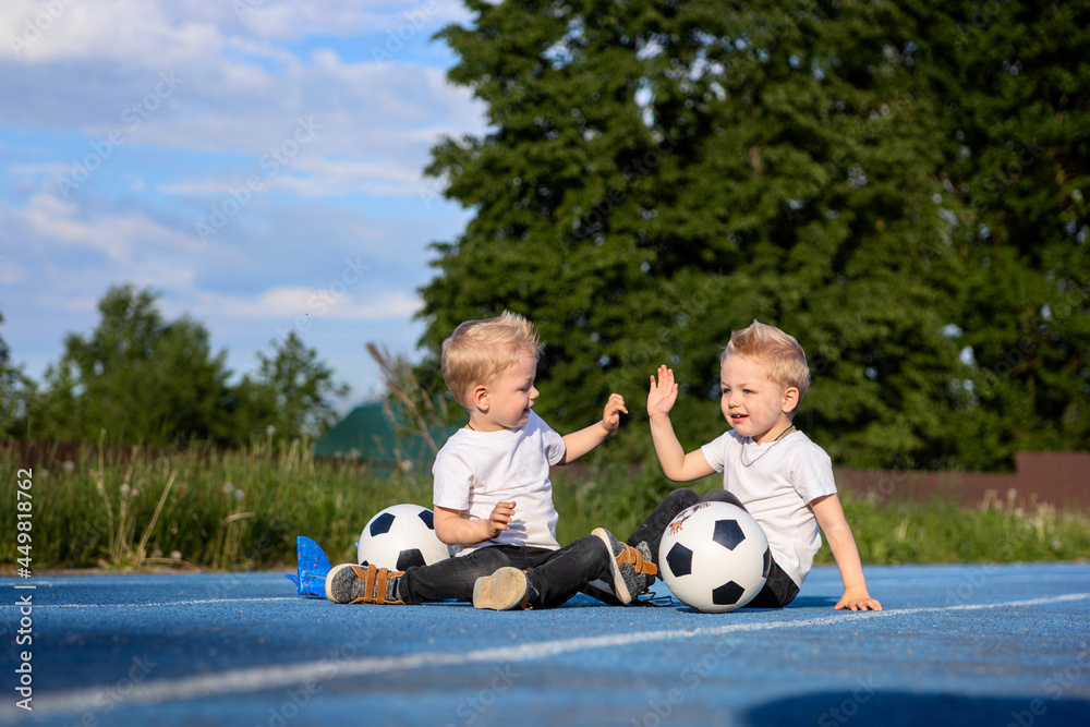 Twin brothers are playing on a walk.Two boys are sitting on the stadium ...
