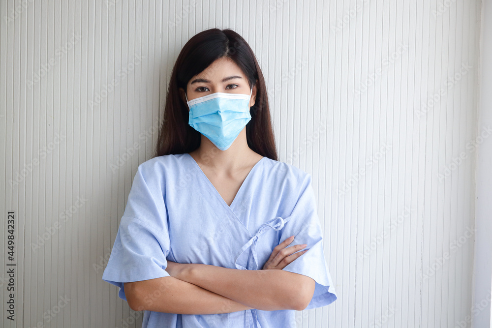 An Asian female patient wearing a mask, folded her arms, leaned against ...
