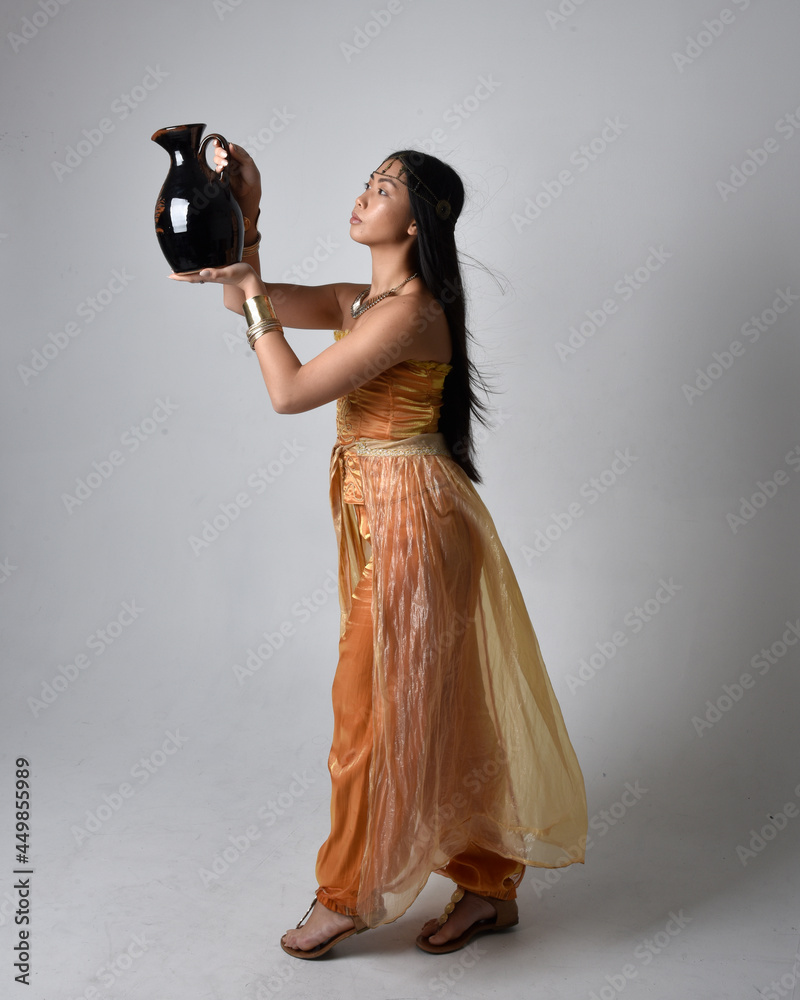 Full length portrait of pretty young asian woman wearing golden Arabian ...