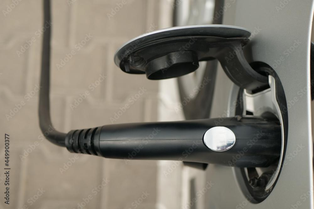 Electric vehicle charging port plugged in EV modern car on parking lot ...
