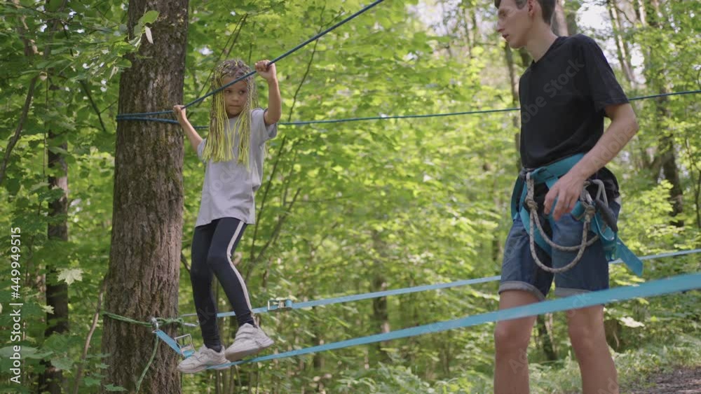 Small girl in climbing equipment in a rope Park. Group of Caucasian ...