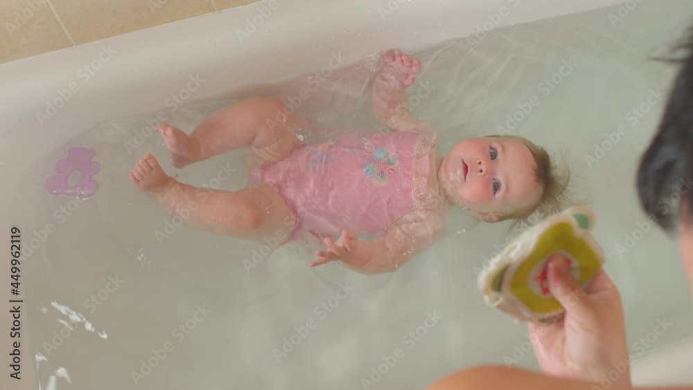 Infant baby floats independently in bathtub. Swimming lesson for baby ...