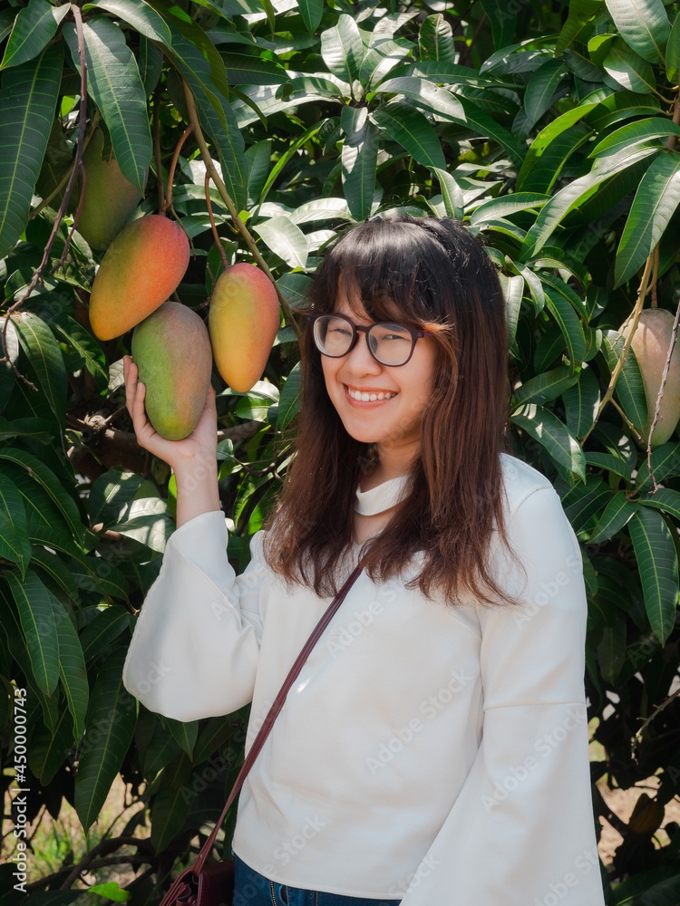 happy Asian woman with eyeglasses pinking fresh rainbow mango or ...