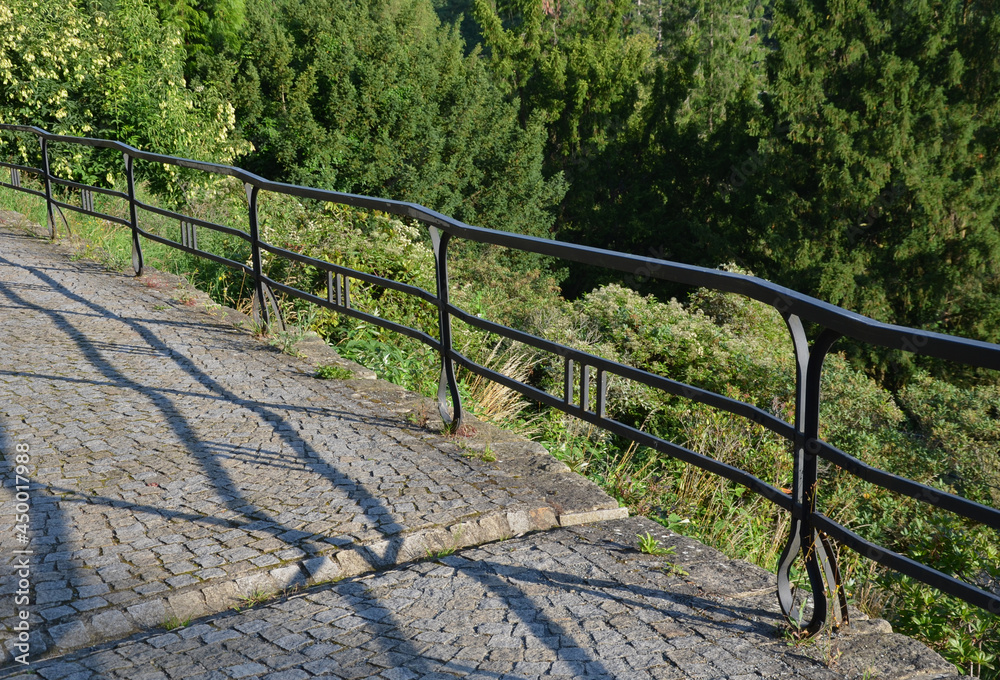 metal black railing copying the slope of a paved park path with ...