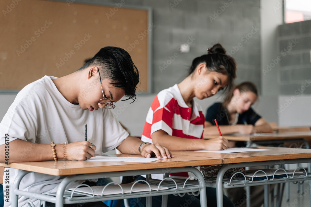 Asian Student writing exam in the college high school classroom - Multi ...