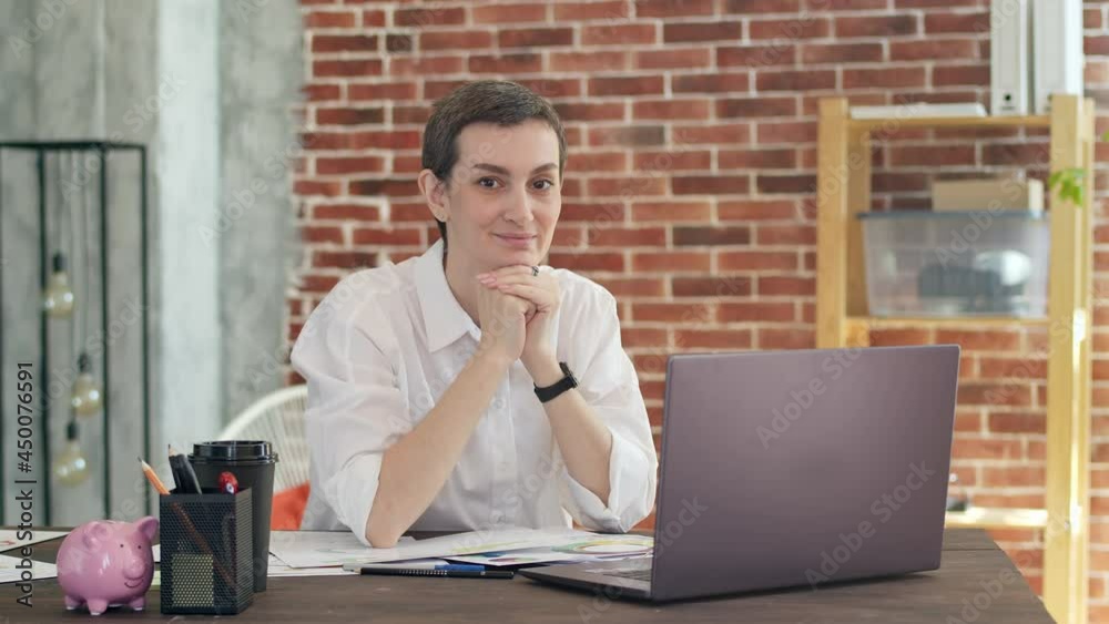 Nice woman in a white shirt sits at an office table propped up chin in ...