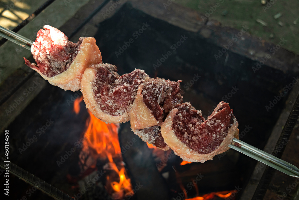 Raw rump steak seasoned with coarse salt on the grill with fire, the ...