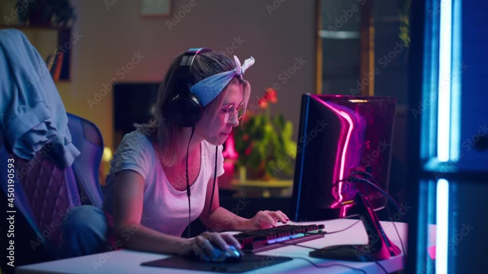 Young woman putting on headphones and playing computer game. Female ...