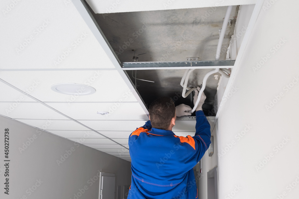 worker pulls a wire over the false ceiling for new internet access ...