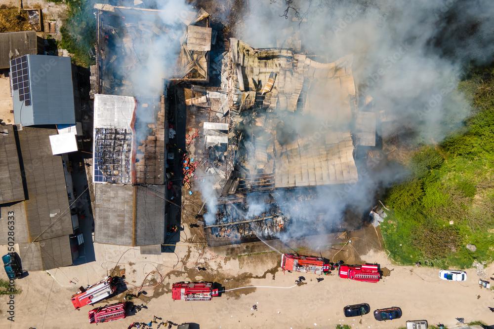 Aerial view of firefighters extinguishing ruined building on fire with ...