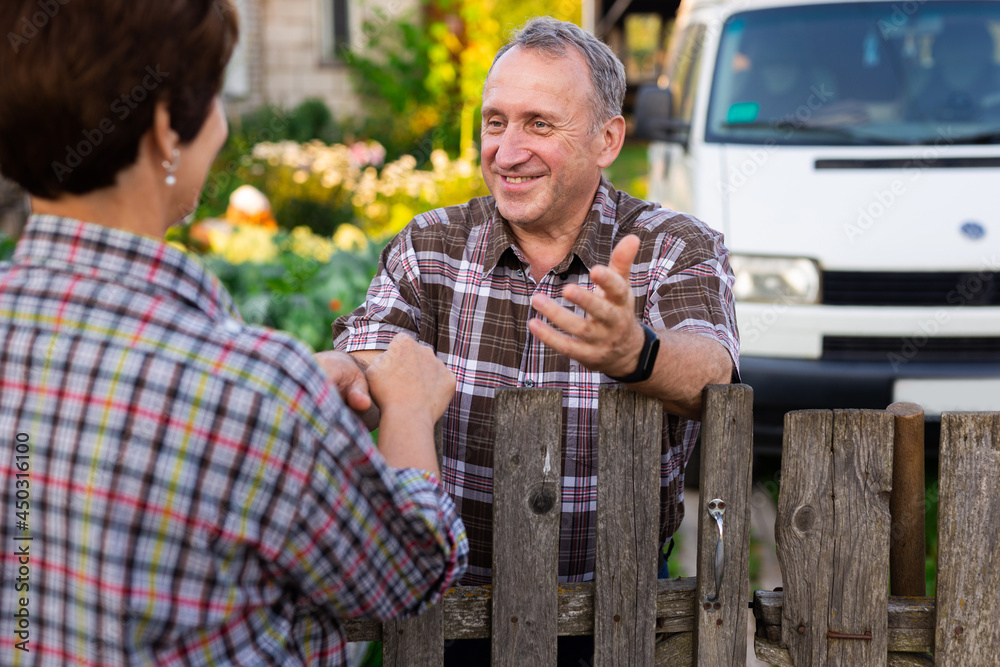 neighbors man and woman chatting near the fence in the village Stock ...