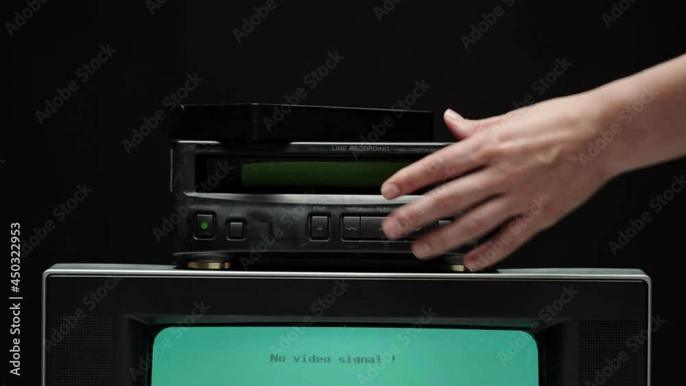 Putting video cassette into recorder. Old retro television with blue ...