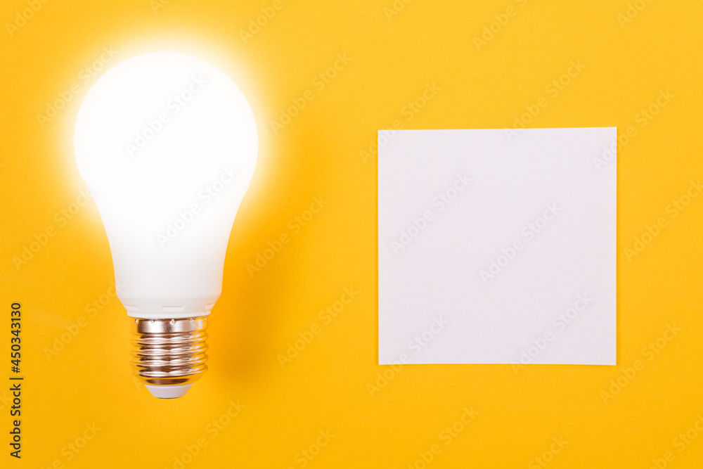 Glowing Power Saving Lamp with White Note Paper Lying on Yellow Table ...