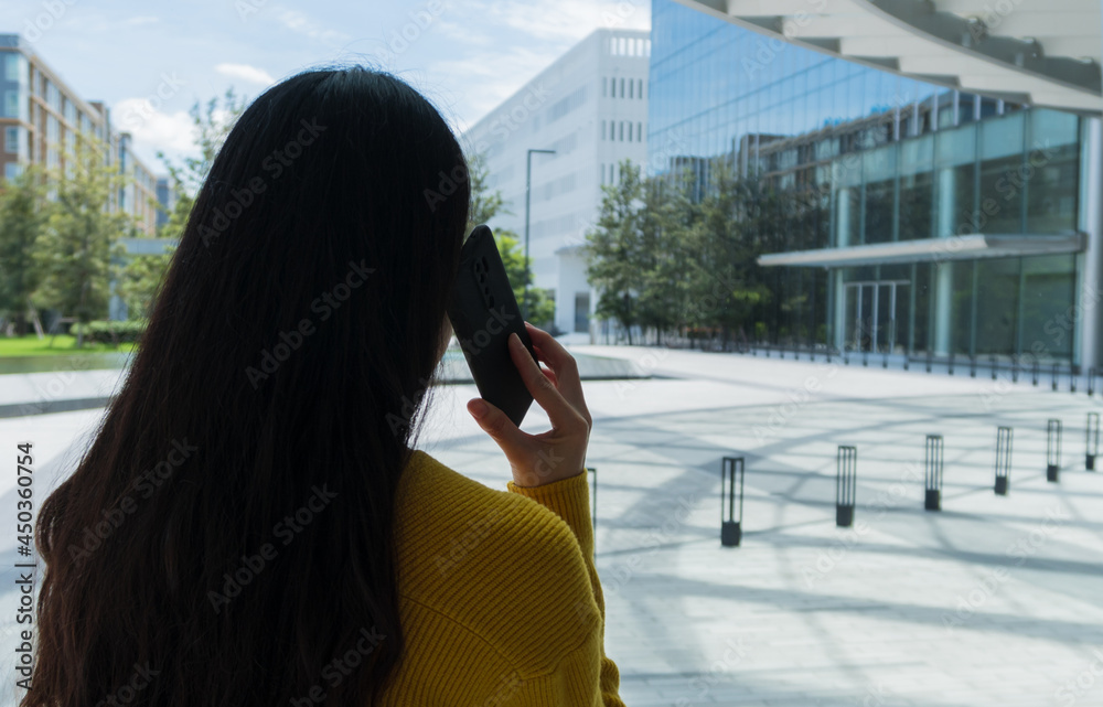 Asian woman with long hair standing on the phone talking. Look at the ...