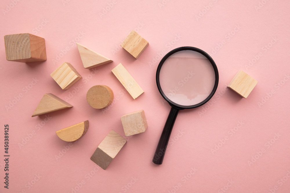 Magnifying glass with a selection of different shaped wooden blocks ...
